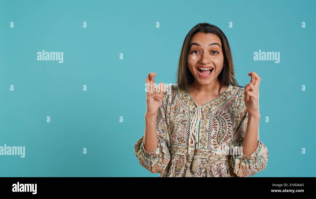 Portrait of upbeat indian woman crossing fingers, making wish, isolated ...