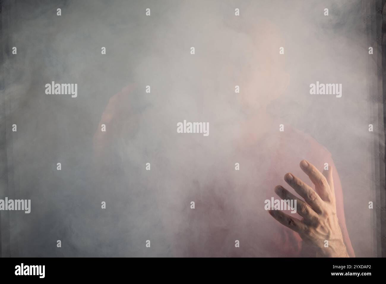 Hands of a white man appearing through thick smoke. Studio portrait ...