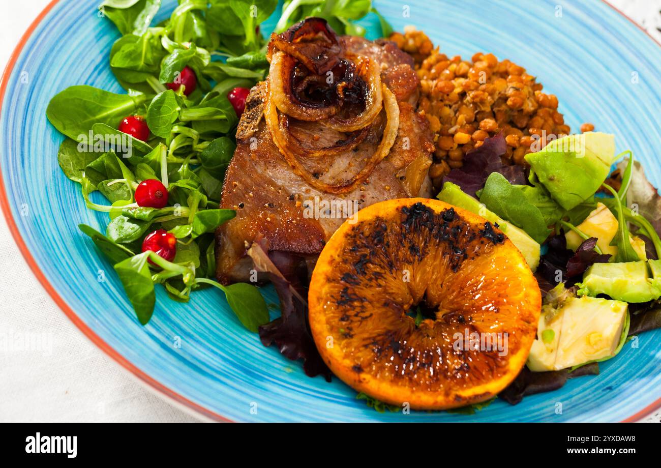 Grilled pork meat with lentils, avocado, greens and grilled orange ...