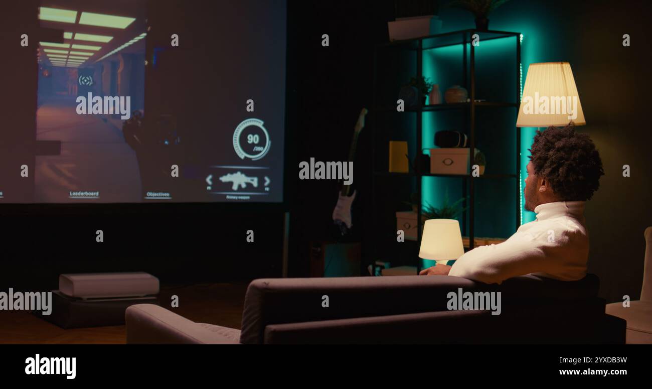 Man sitting on couch, playing first person shooter videogame on smart ...