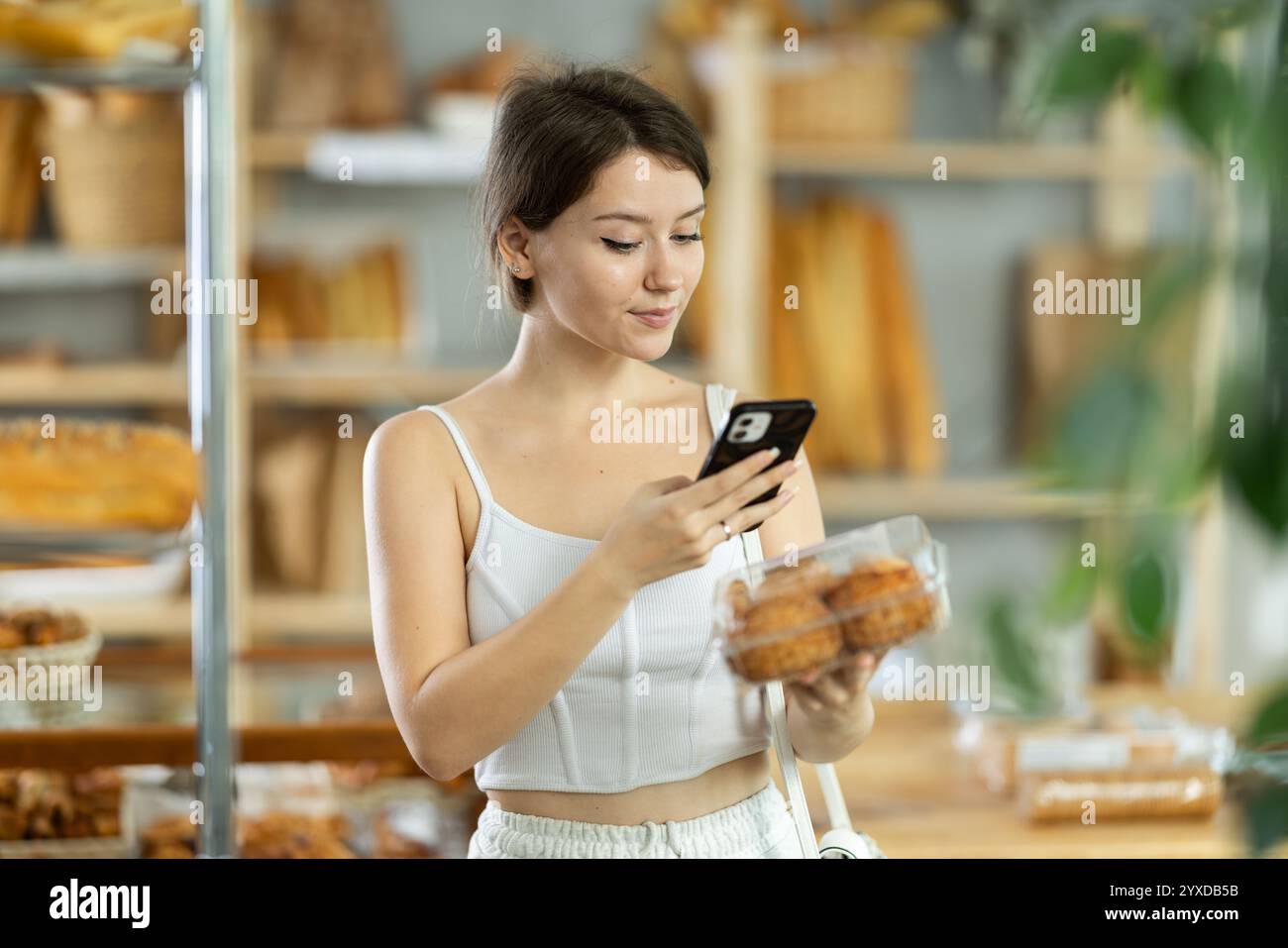 Female customer scanning QR code on label of fresh baked goods in ...