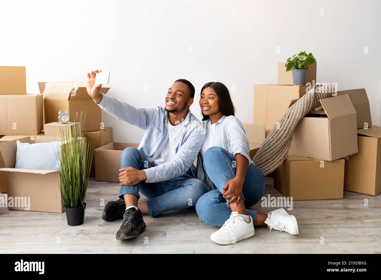 Happy black couple moving to their own home and taking selfie among ...