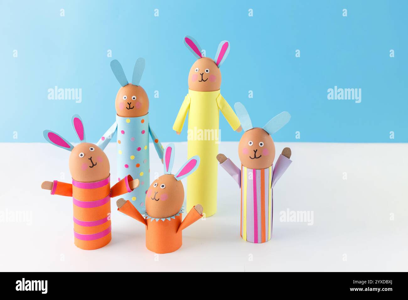Handmade Easter bunny crafts using colored paper and eggs on a blue ...