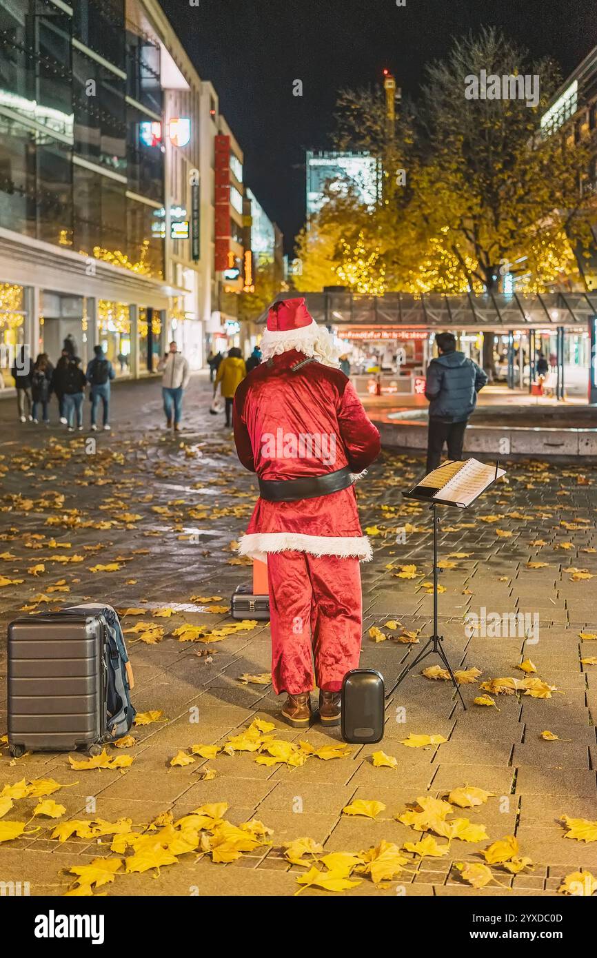 Street performer dressed as Santa Claus playing music on city street at ...