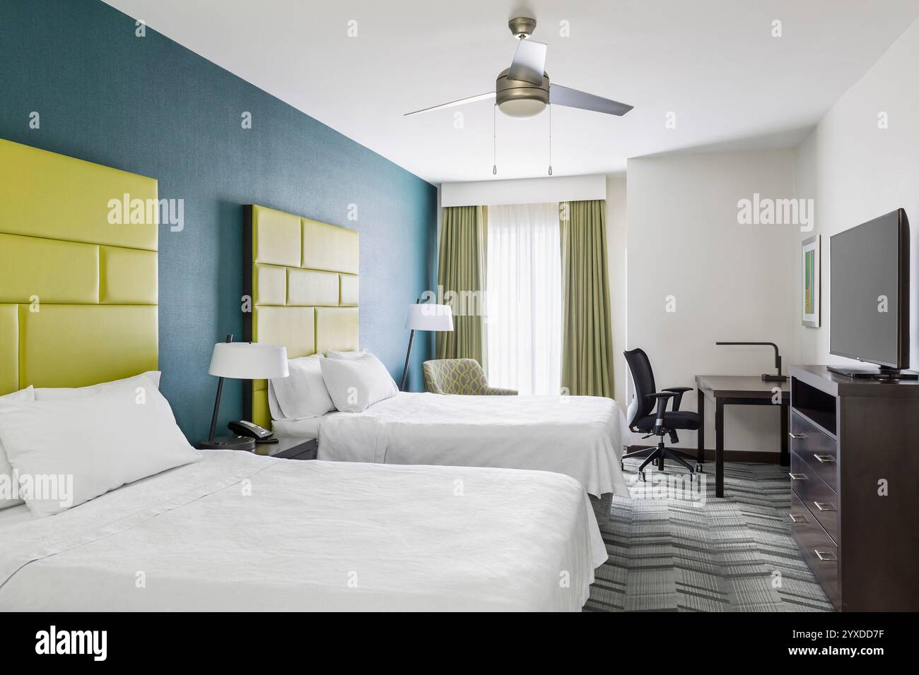 Colorful hotel room with blue wall and green headboards and curtains ...