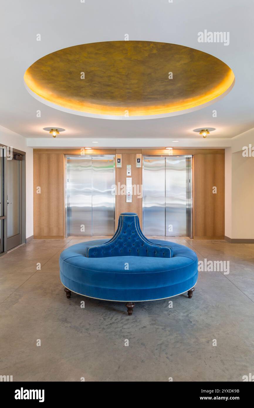 Blue velvet round lobby sofa in front of two elevators in apartment ...