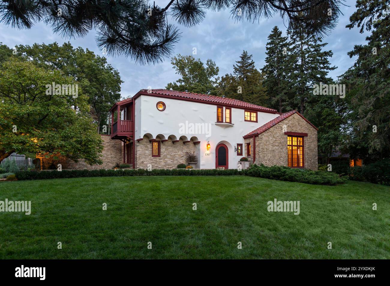 Front exterior of Spanish Eclectic style house at dusk with interior ...