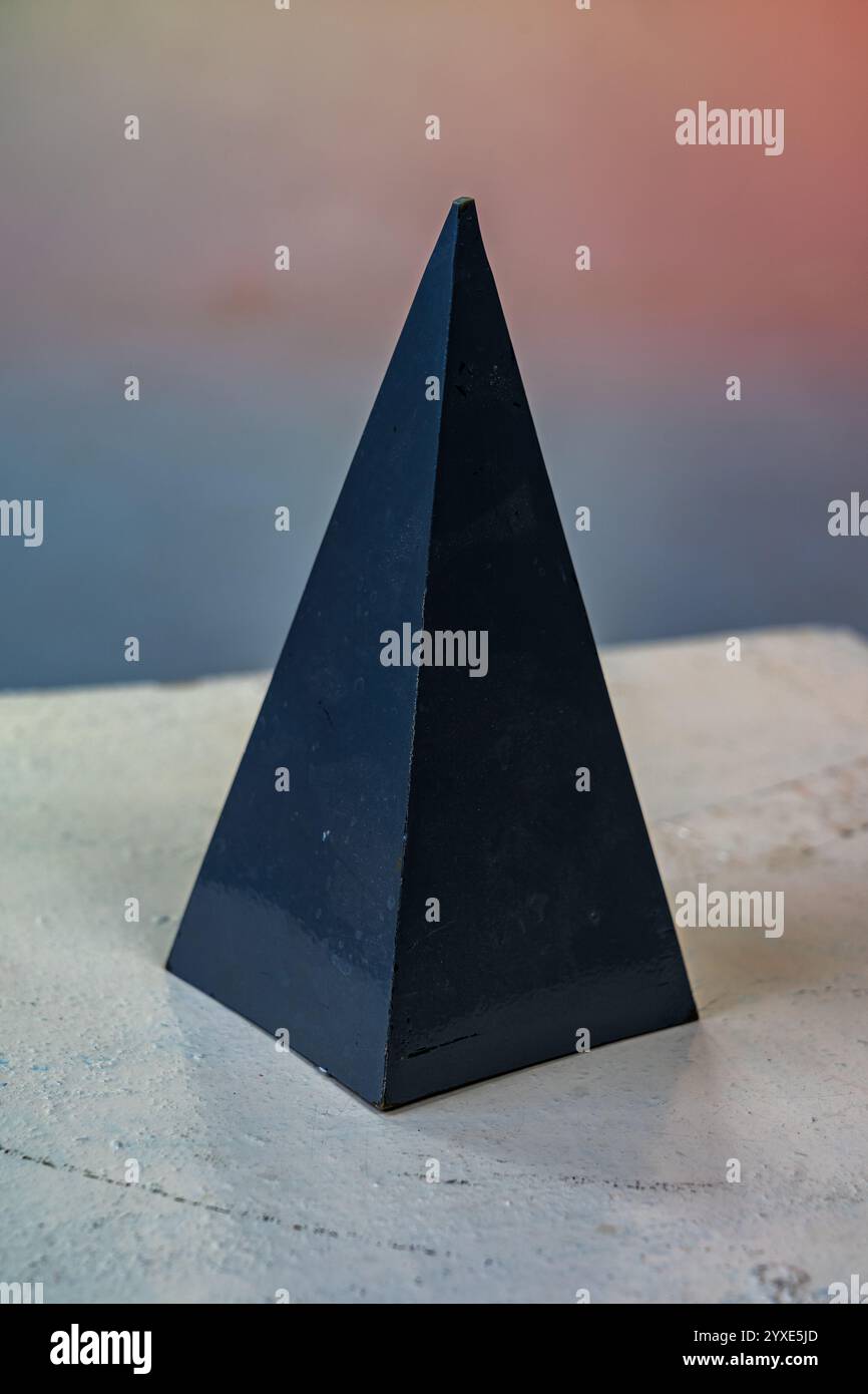 A sleek black pyramid stands on a light-colored surface, showcasing its ...