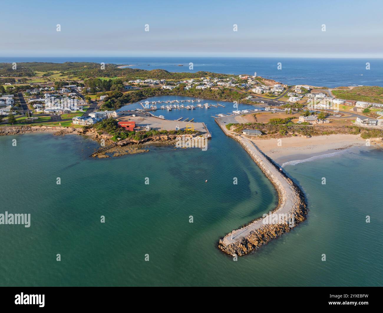 Aerial view of a curved breakwater leading into a coastal marina at ...