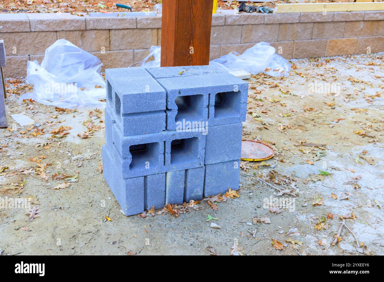 Concrete blocks are neatly stacked on sandy ground surrounded by fallen ...