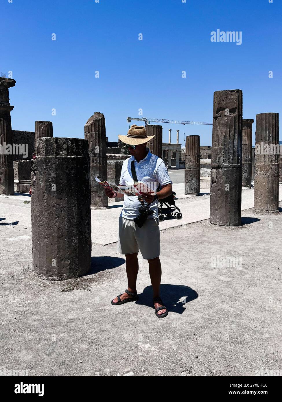 A tourist stands amidst ancient ruins, studying a map intently ...