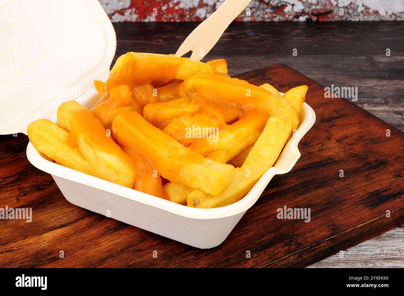Chips and chip shop curry sauce in a take away box with wooden fork ...