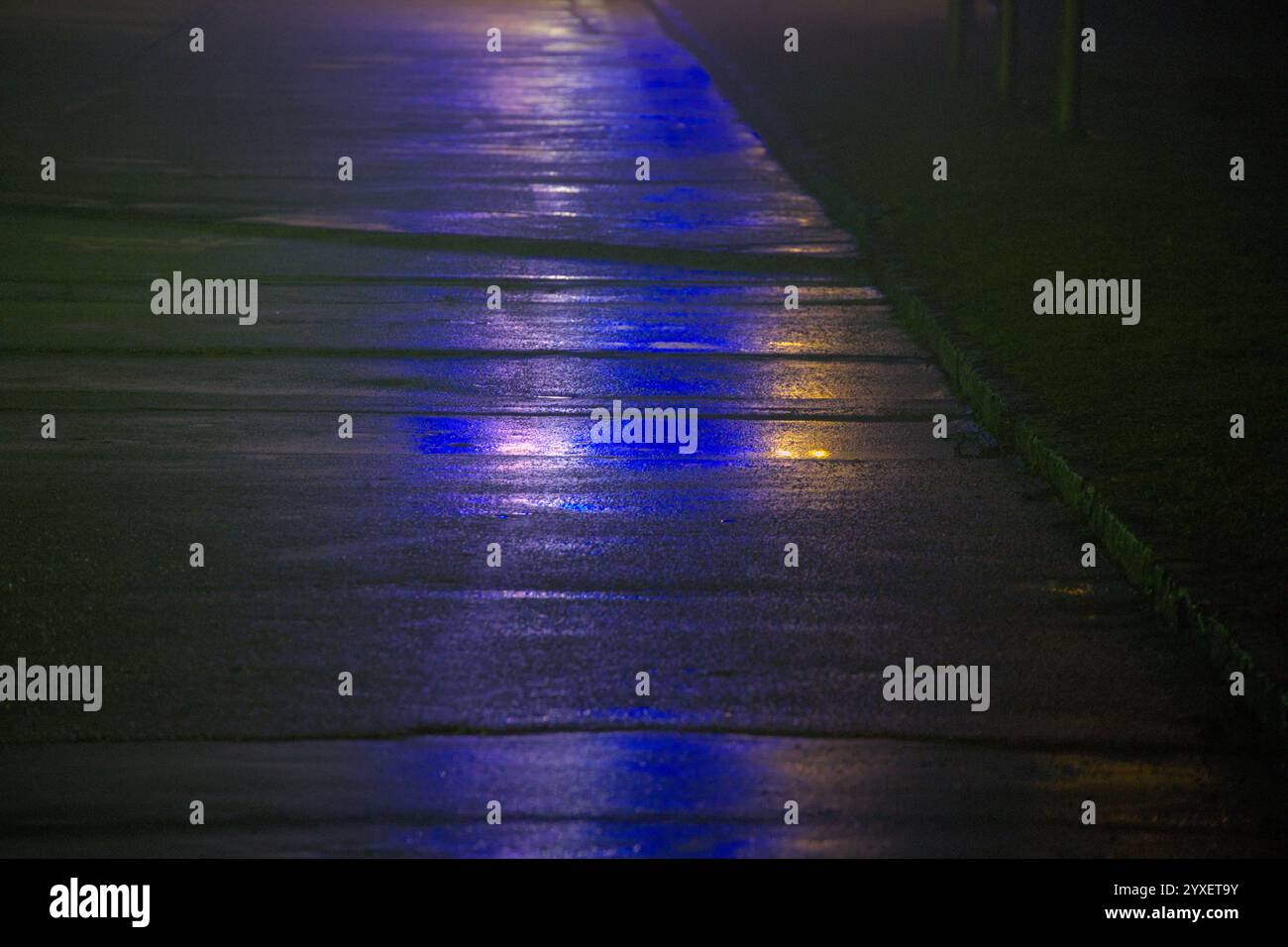 Colorful reflections of neon and streetlights on a wet pavement at ...