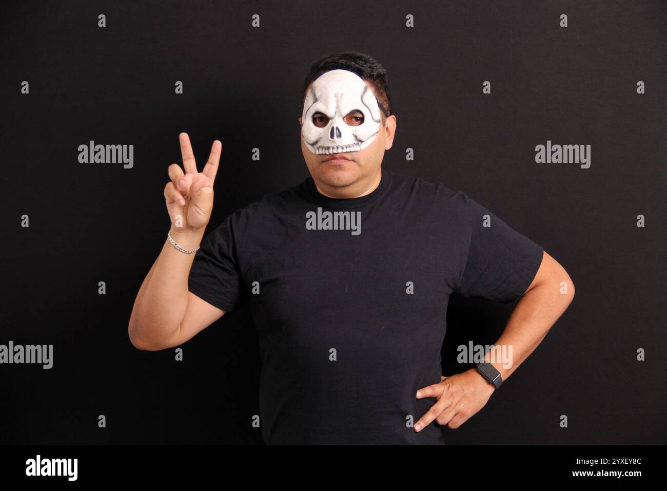 Mexican adult man wears skull mask and makes victory sign with fingers ...
