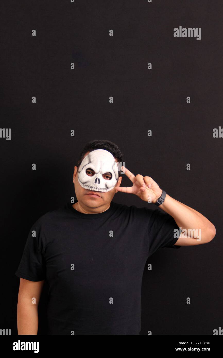 Mexican adult man wears skull mask and makes victory sign with fingers ...