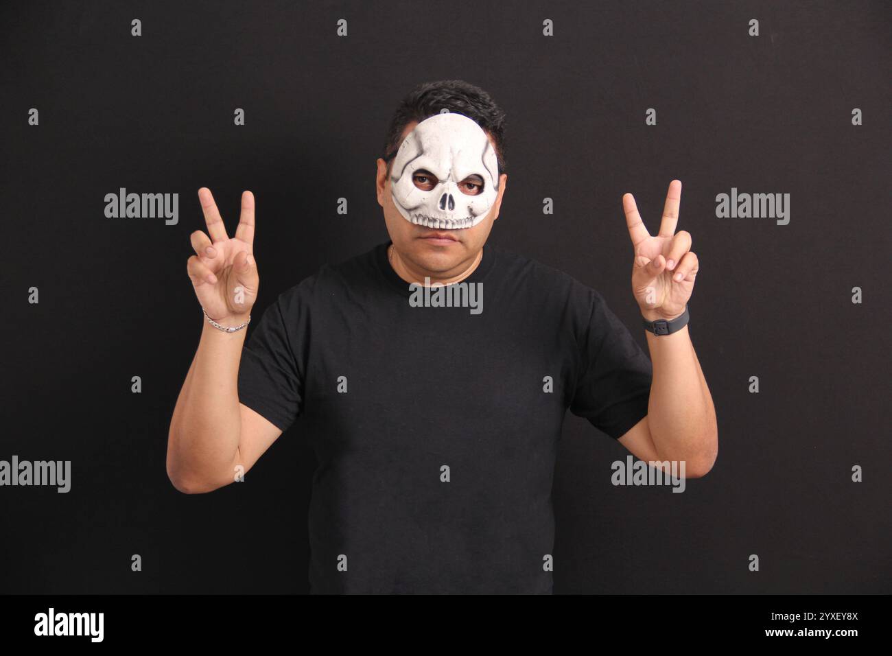 Mexican adult man wears skull mask and makes victory sign with fingers ...