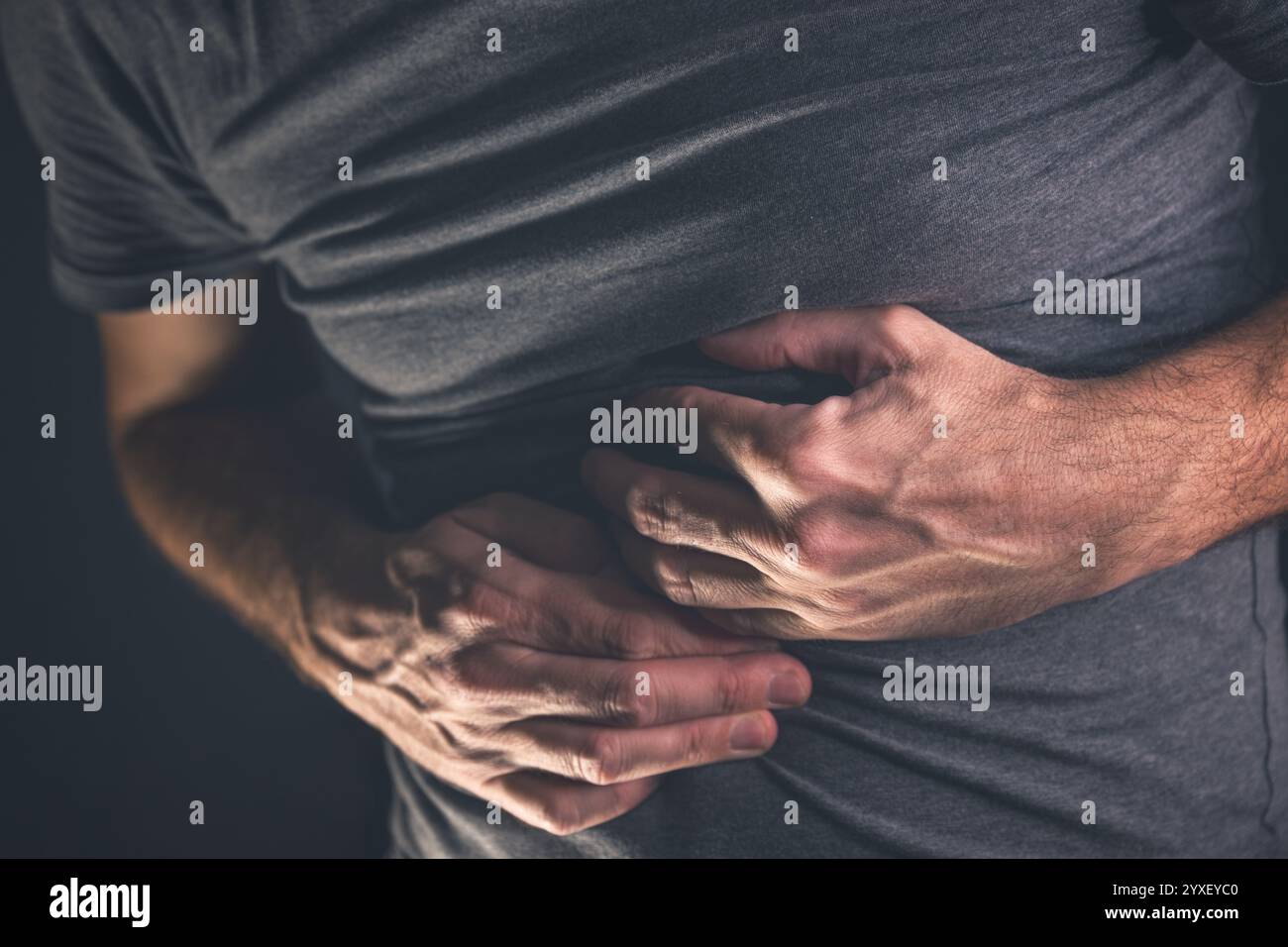 Abdominal pain, man with severe stomachache pressing the belly with his hands, selective focus ...