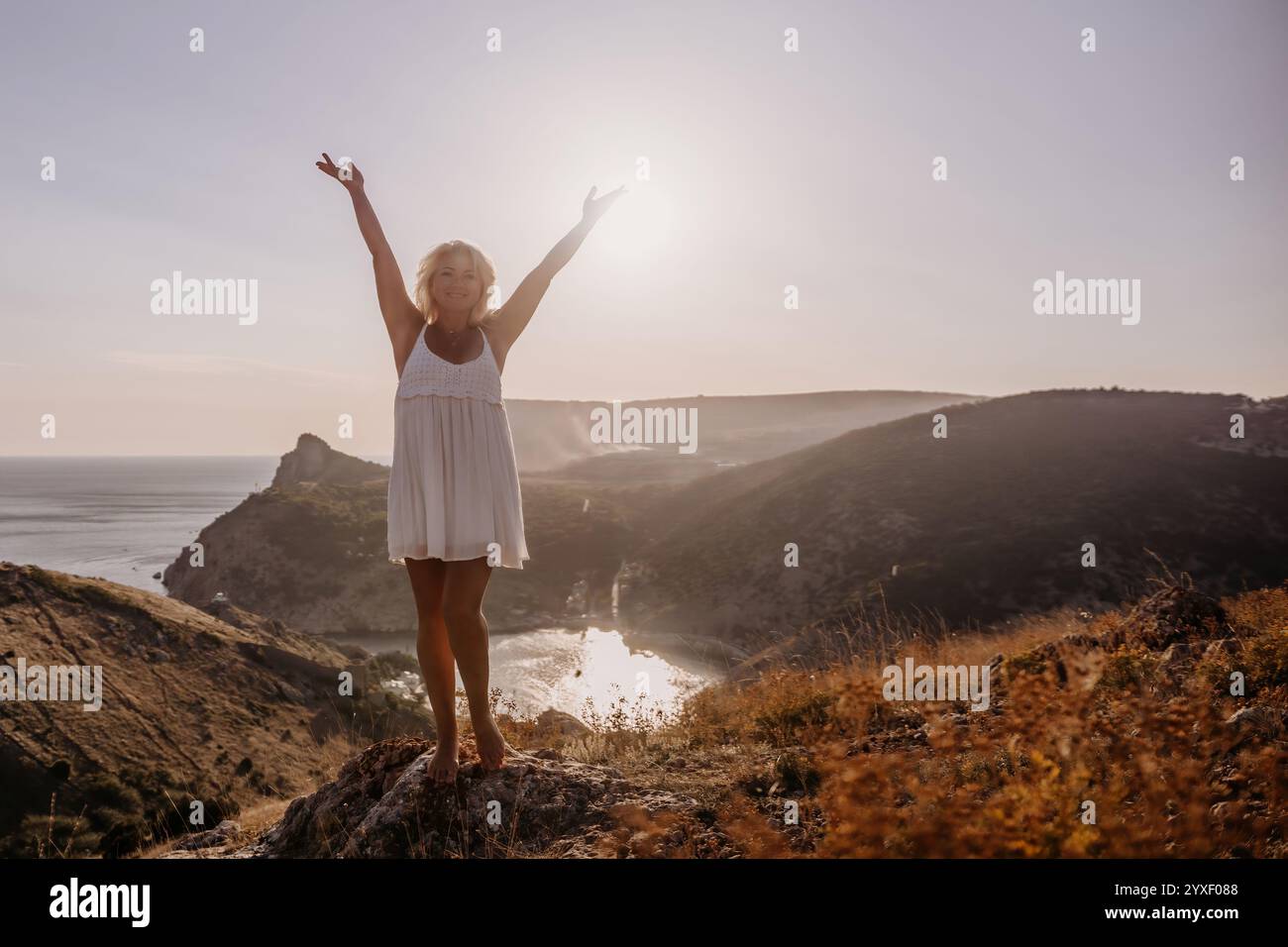 woman standing hill with her arms raised in the air, looking up at the ...