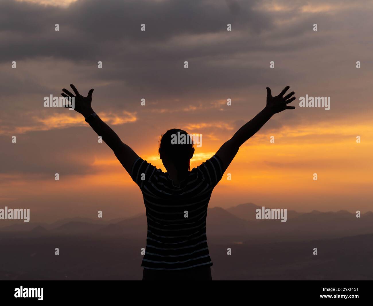 Silhouette of a young woman relaxing in the summer sunset outdoors. A ...
