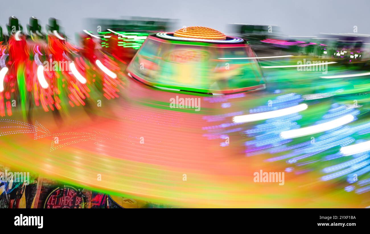 London, UK. 15th Dec, 2024. A vibrant fairground ride illuminates the ...