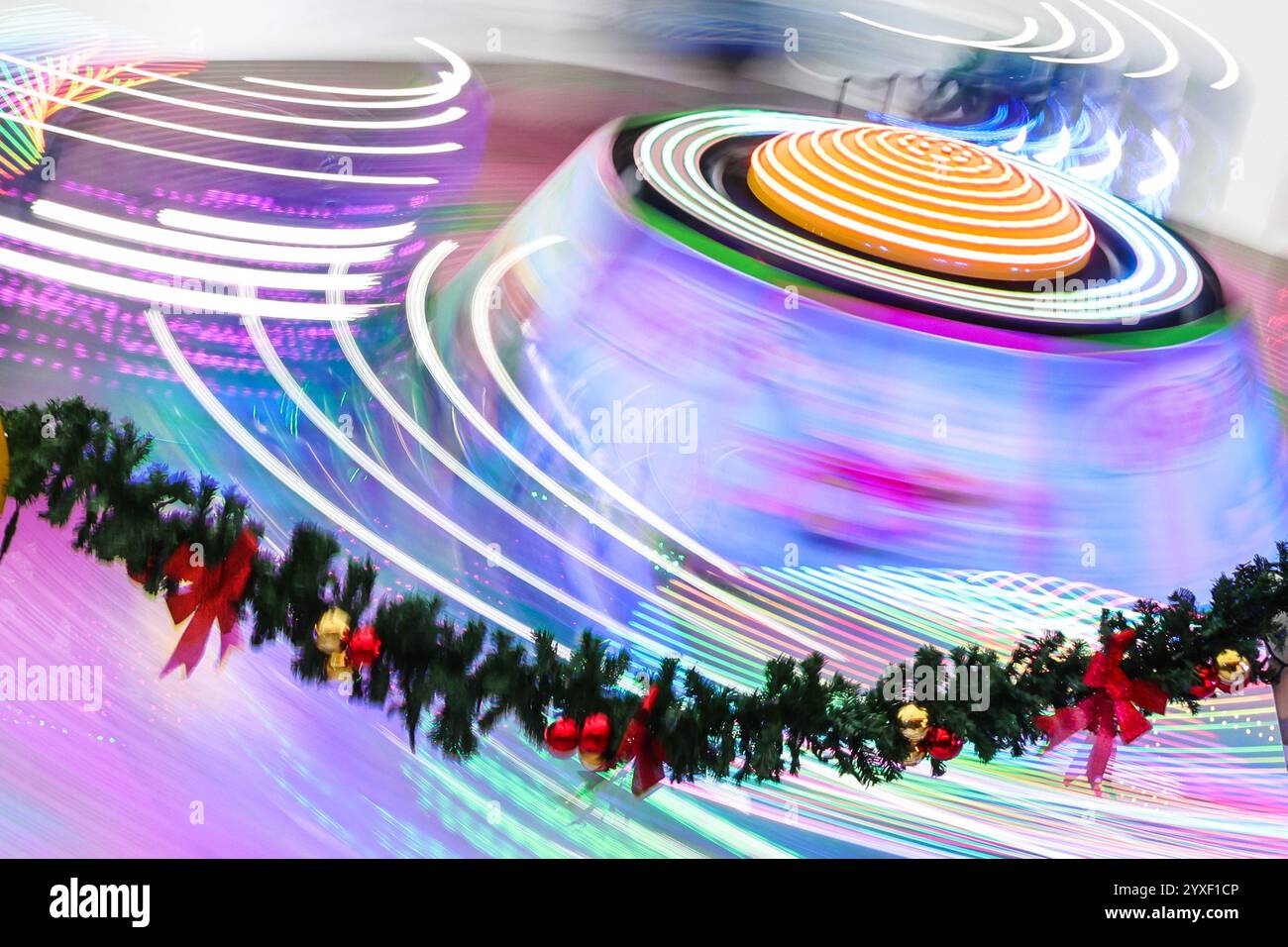 London, UK. 15th Dec, 2024. A vibrant fairground ride illuminates the ...