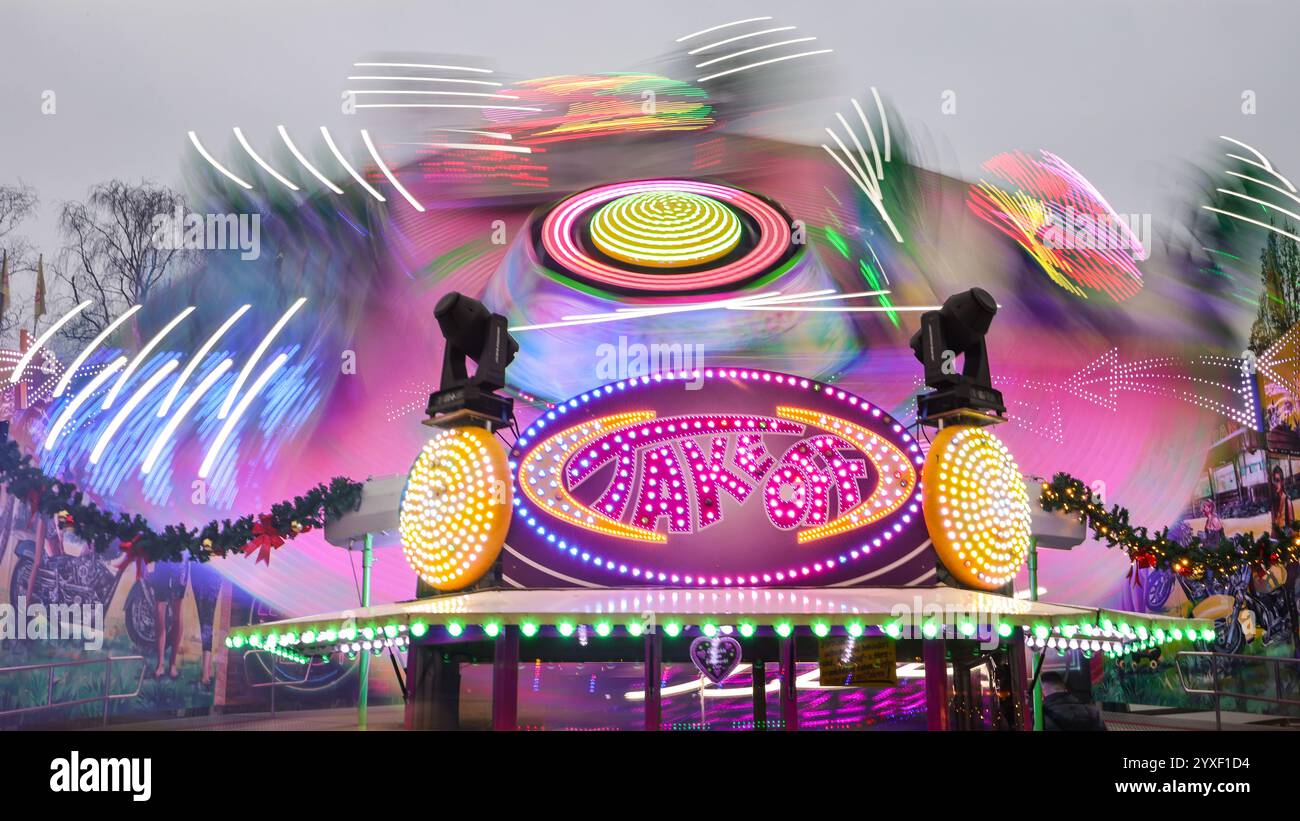 London, UK. 15th Dec, 2024. A vibrant fairground ride illuminates the ...