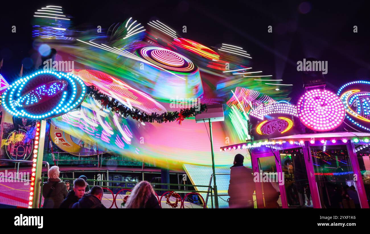 London, UK. 15th Dec, 2024. A vibrant fairground ride illuminates the ...