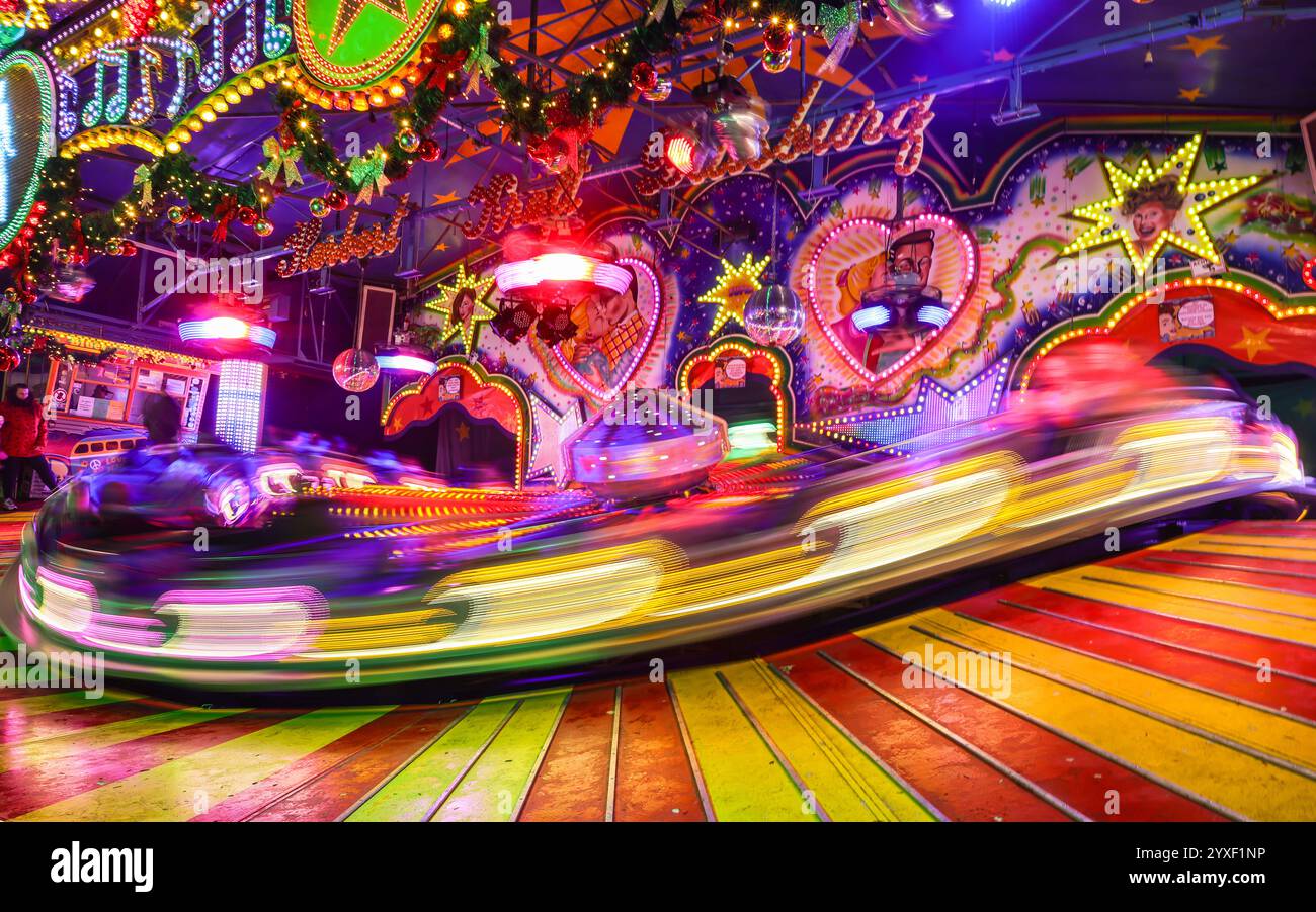 London, UK. 15th Dec, 2024. A vibrant fairground ride illuminates the ...