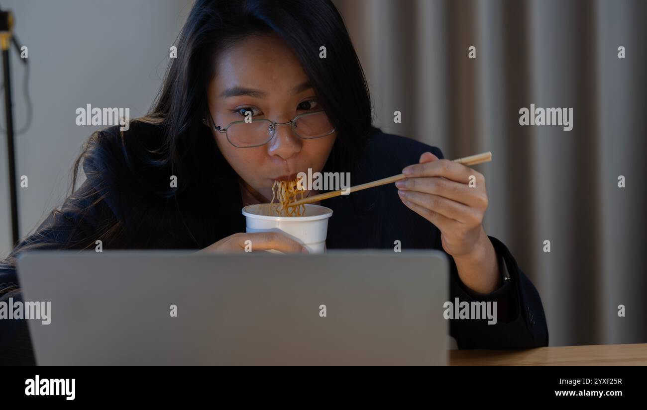 Female businesswoman, manager, employee is eating instant noodles ...