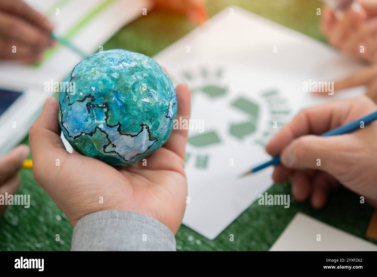 Green Earth Planet model on man hand with a green business meeting ...