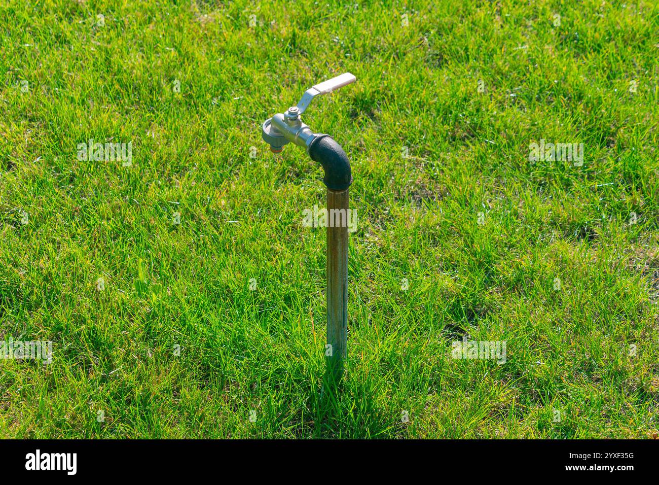A standalone outdoor water tap, mounted on a vertical metal pipe, set ...