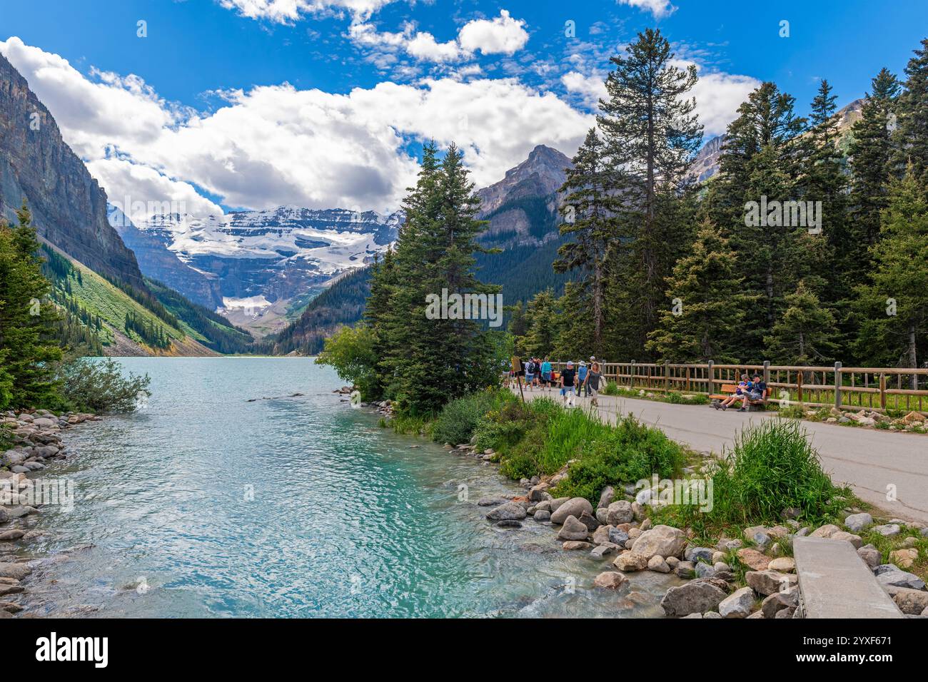 People hiking along Lake Louise with Victoria Glacier in background ...