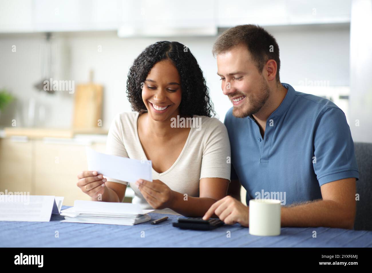 Happy couple reading bank statement in the kitchen at home Stock Photo ...