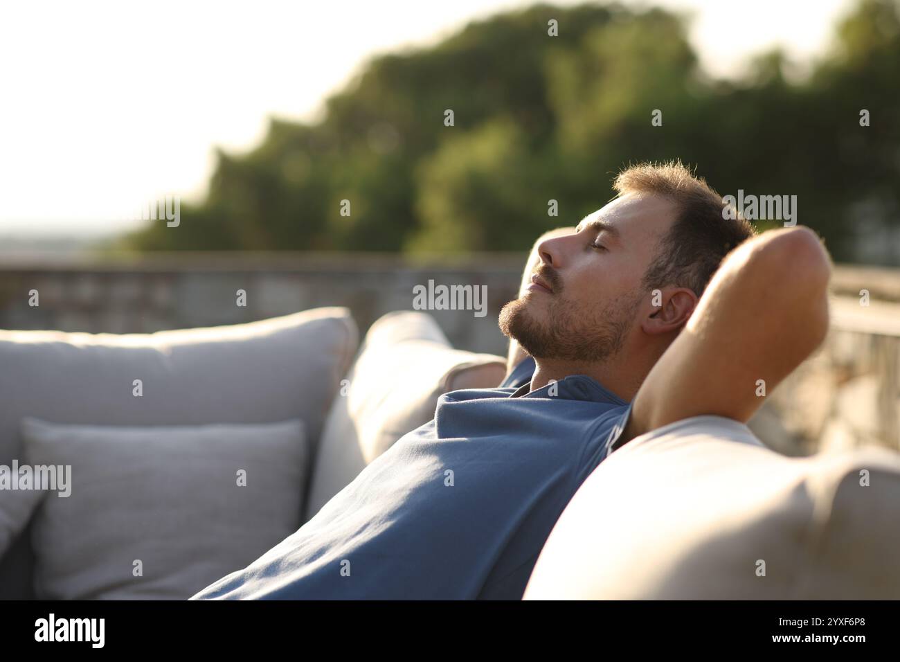 Side view portrait of a relaxed man resting sitting on an exterior sofa ...