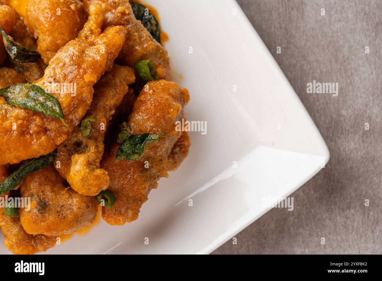 Crispy fried dori fish coated with salted egg plated on a white plate ...