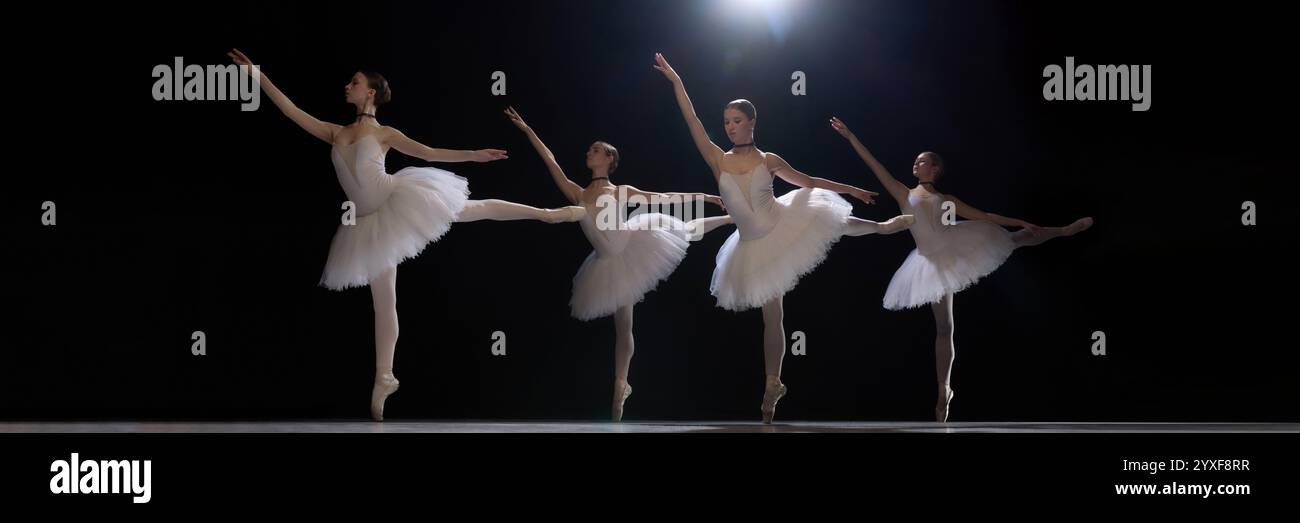 Four ballet dancers performing synchronized arabesque in white tutus ...