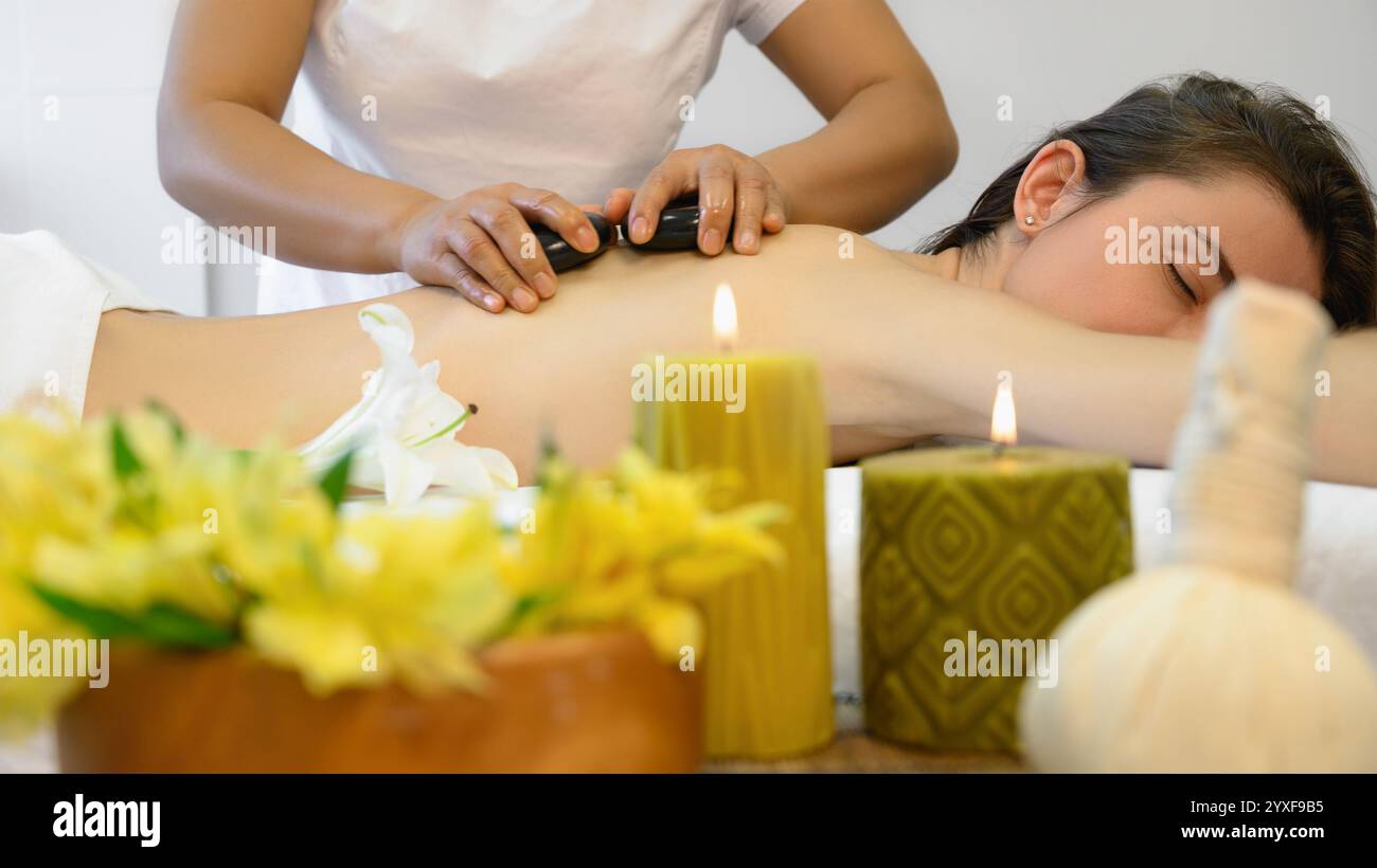 Young woman relaxing in spa salon at hot stone body massage. Stone ...