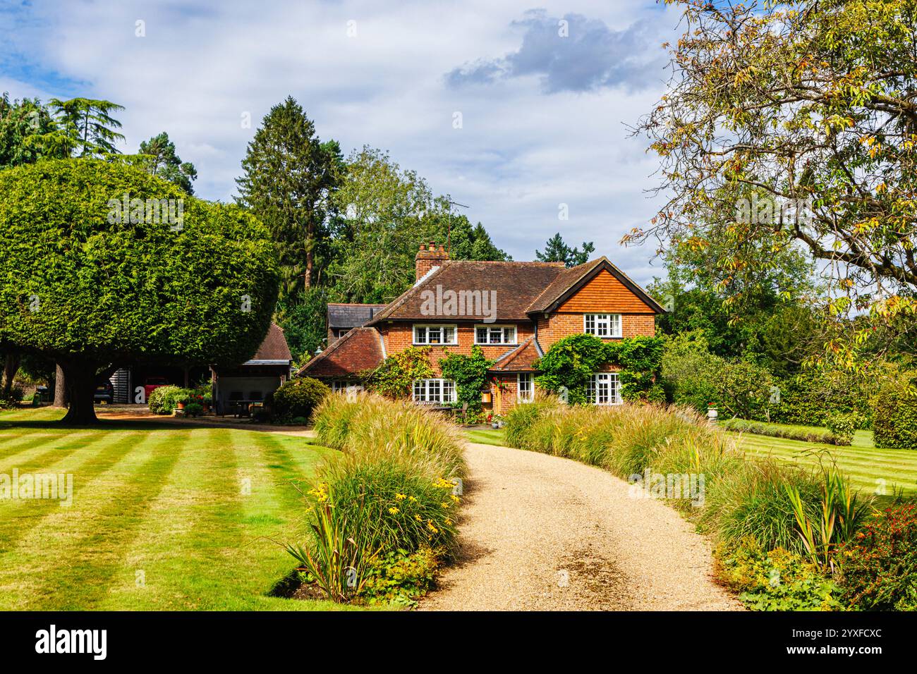 A large detached house and front garden with stripy lawn in the country ...