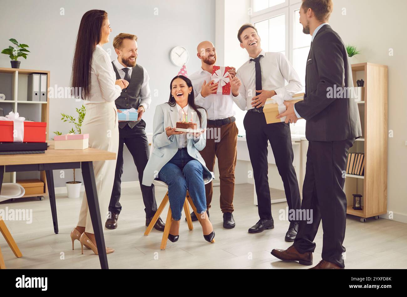 People congratulating colleague with birthday giving her cake and gift ...