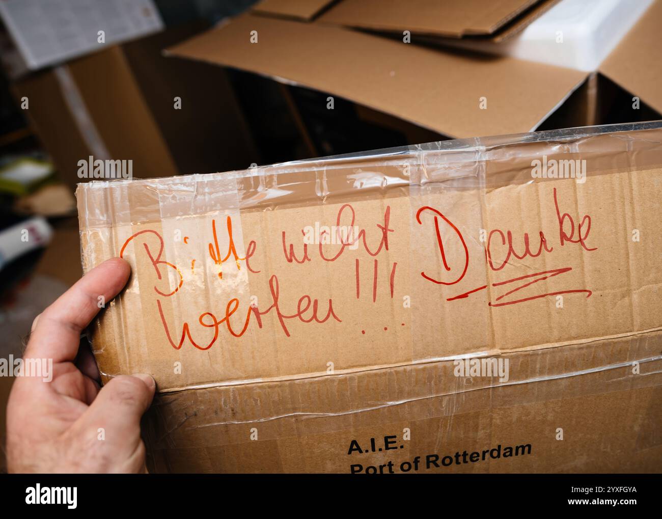 Close-up of a cardboard box marked with a handwritten German warning ...