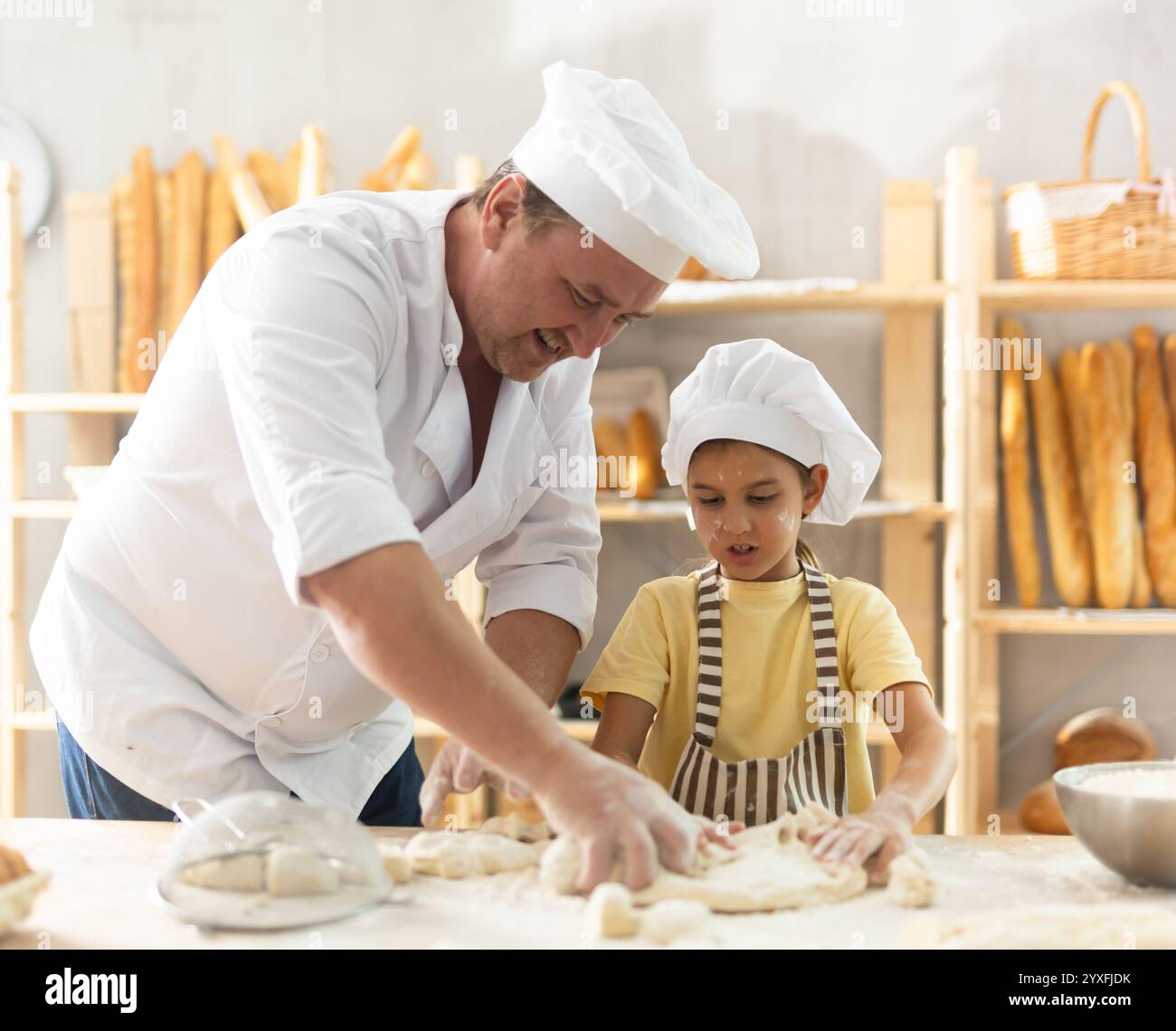 Father and daughter roll out dough together to make delicious bread ...