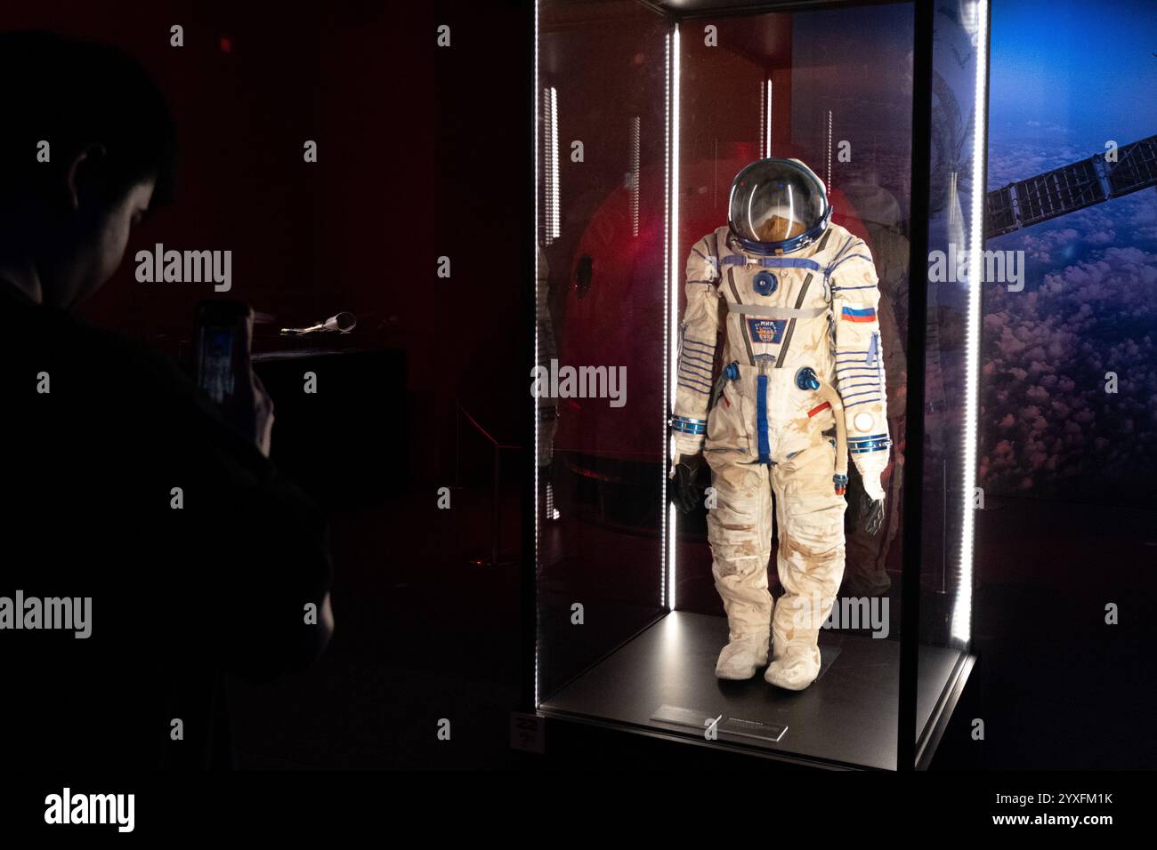 A visitor takes a photo of an astronaut suit on display during the ...