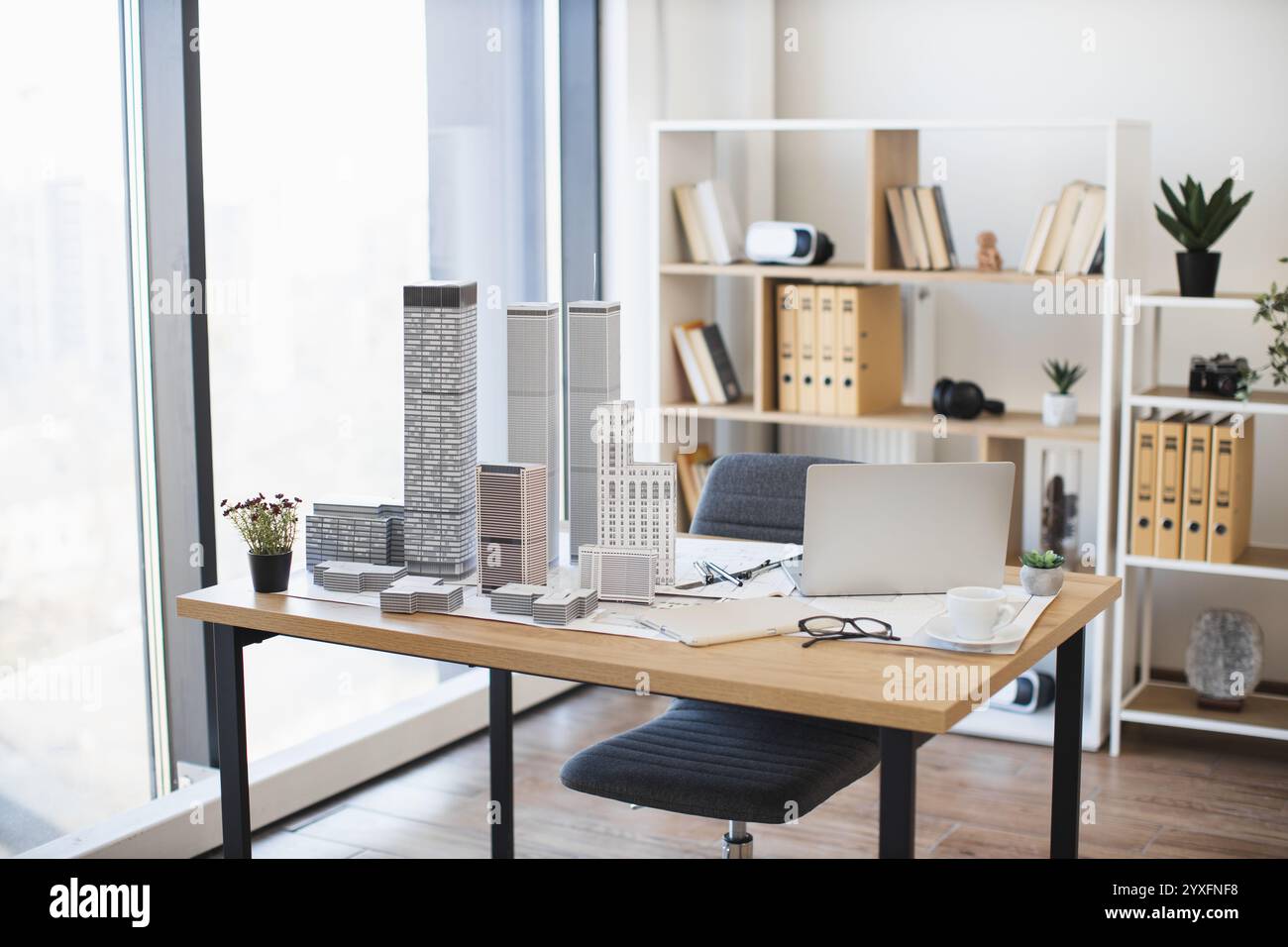 Modern office desk features architectural model and laptop setup ...