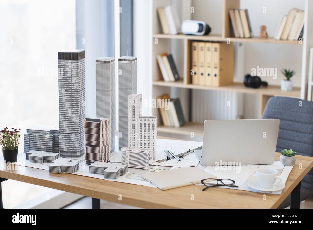 Modern office desk features architectural model and laptop setup ...