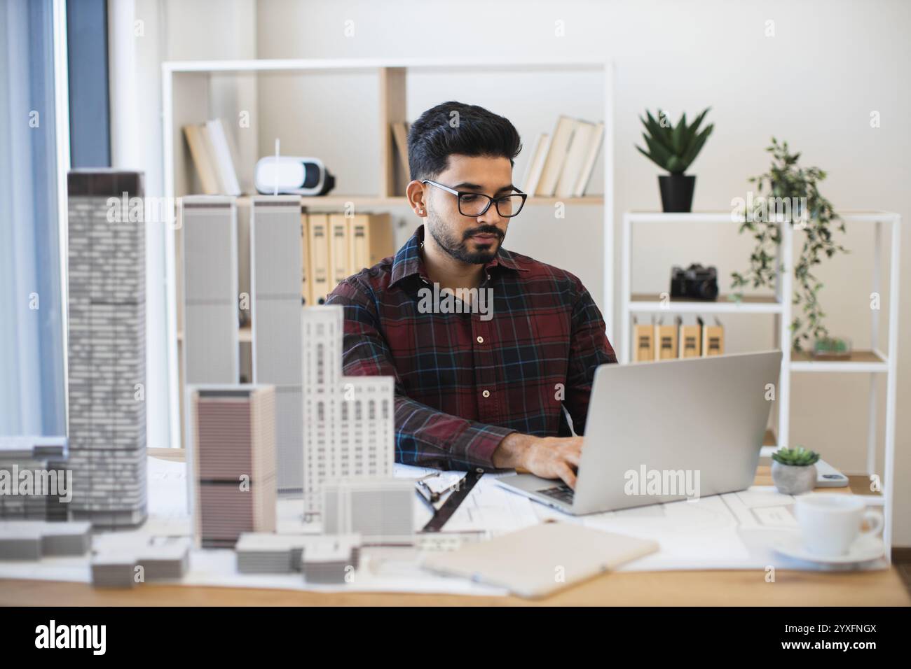Young Indian male architect working on laptop, designing modern city ...
