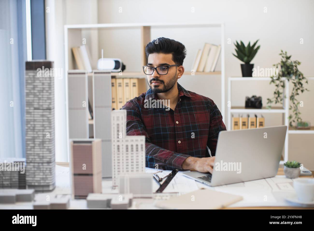 Young Indian male architect working on laptop designing modern urban ...