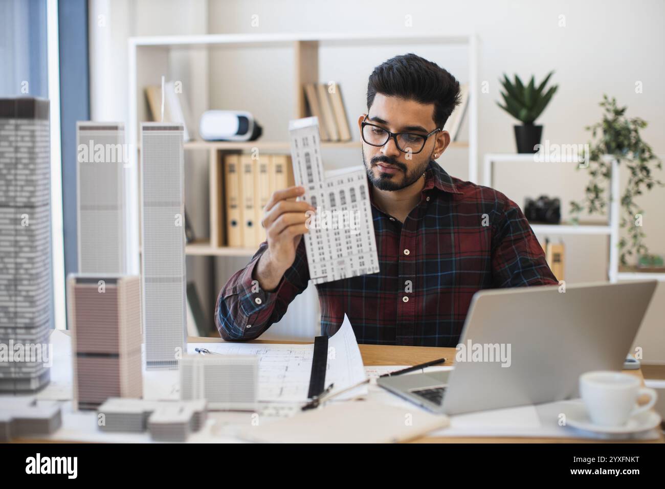 Young Indian male architect examining city model, working on urban ...
