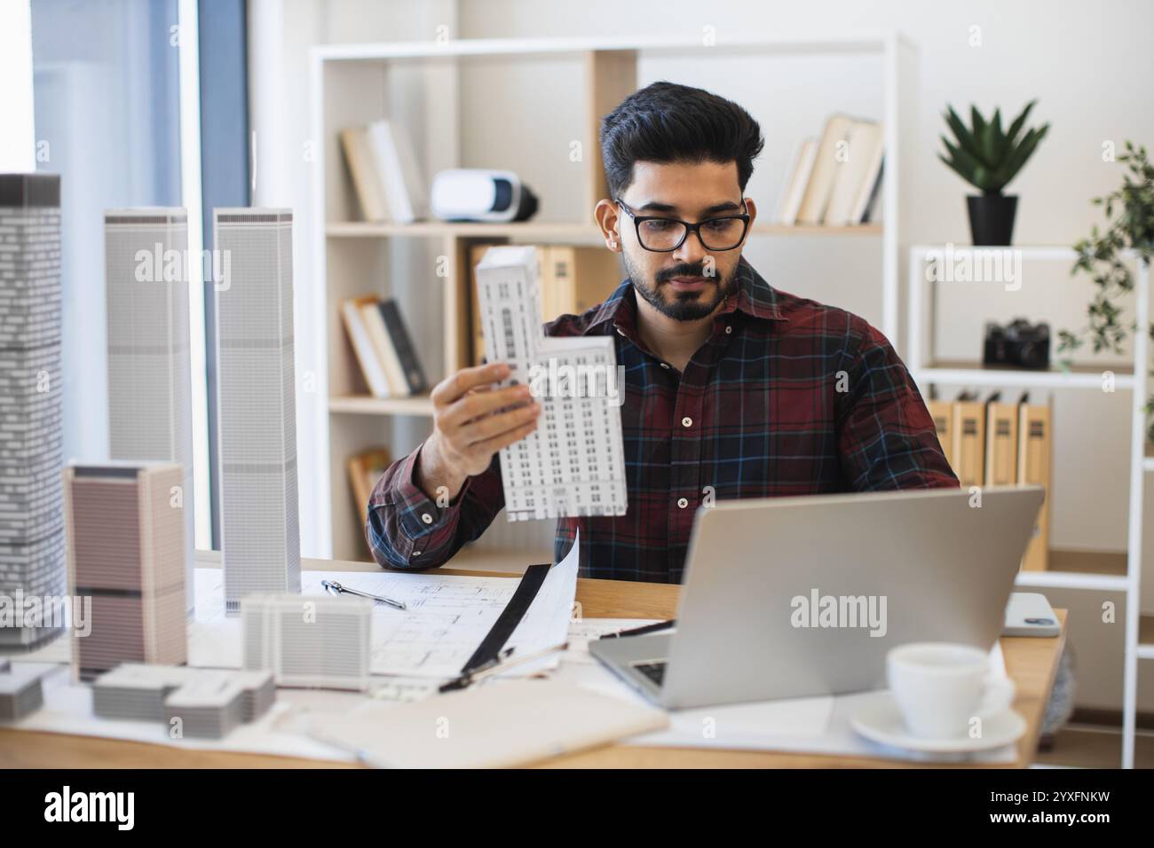 Young Indian man designing architectural model in office environment ...