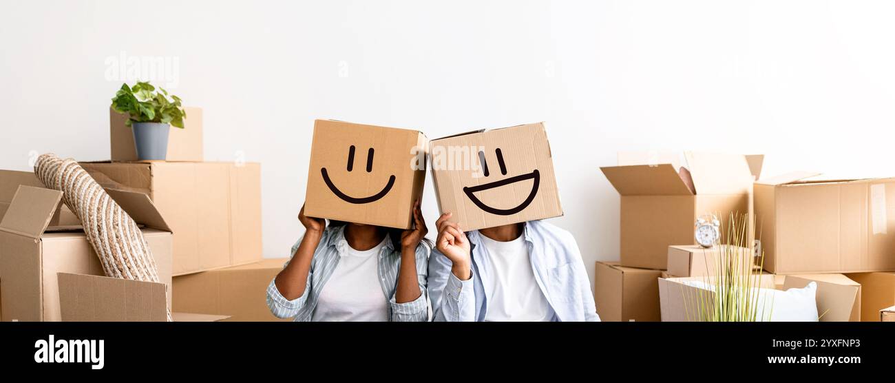 Moving and real estate concept. Black couple with cardboard boxes with ...