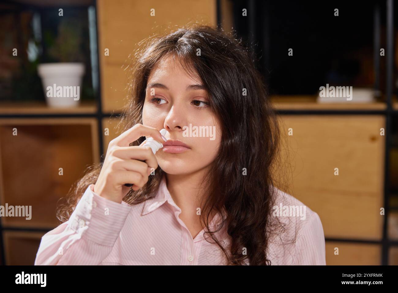 Young woman sitting at table, suffering from allergy, runny nose or ...